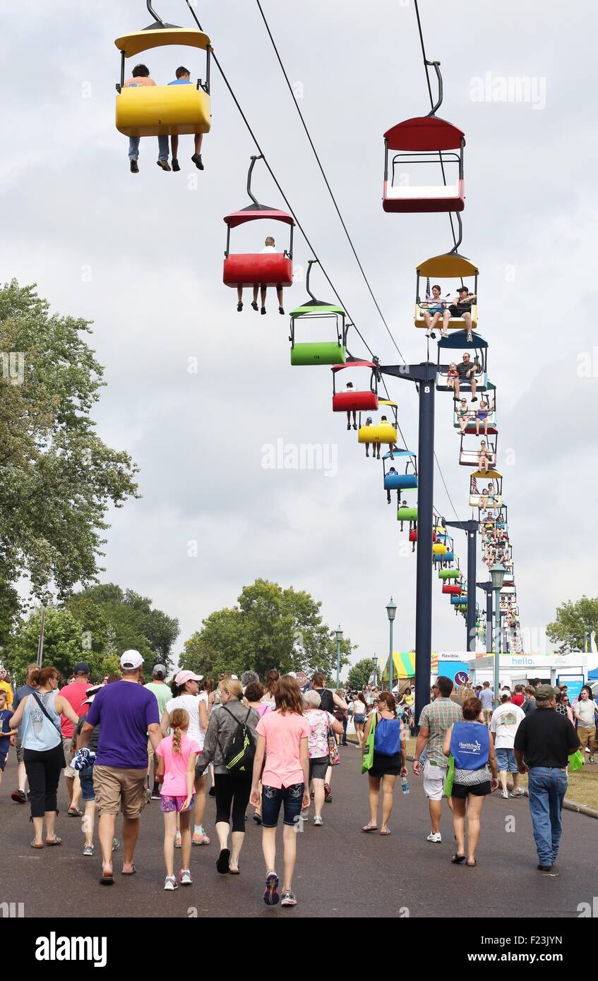 Crowds of people walking under a colorful chair lift ride at the ...
