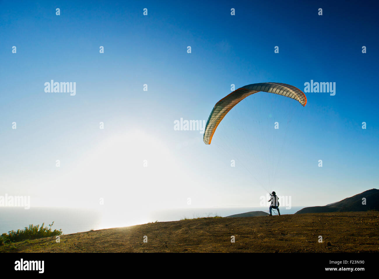 A paraglider launches over the Pacific Ocean on a long, gliding flight ...
