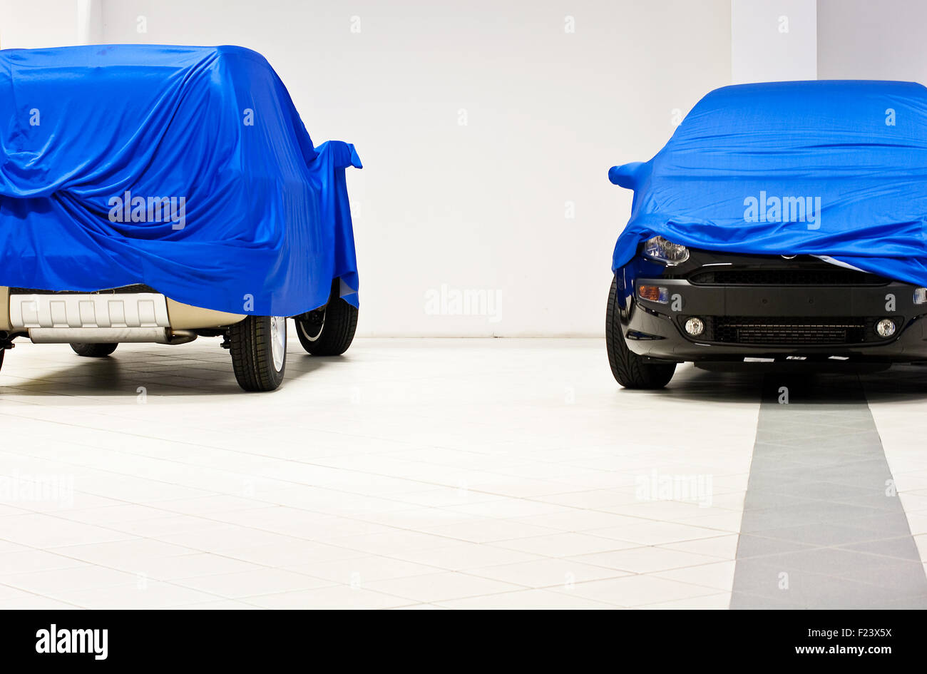 Car covered by a blue sheet in a dealership Stock Photo - Alamy