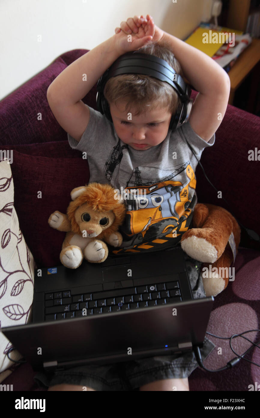Small boy watching video on laptop computer with headphones Stock Photo ...