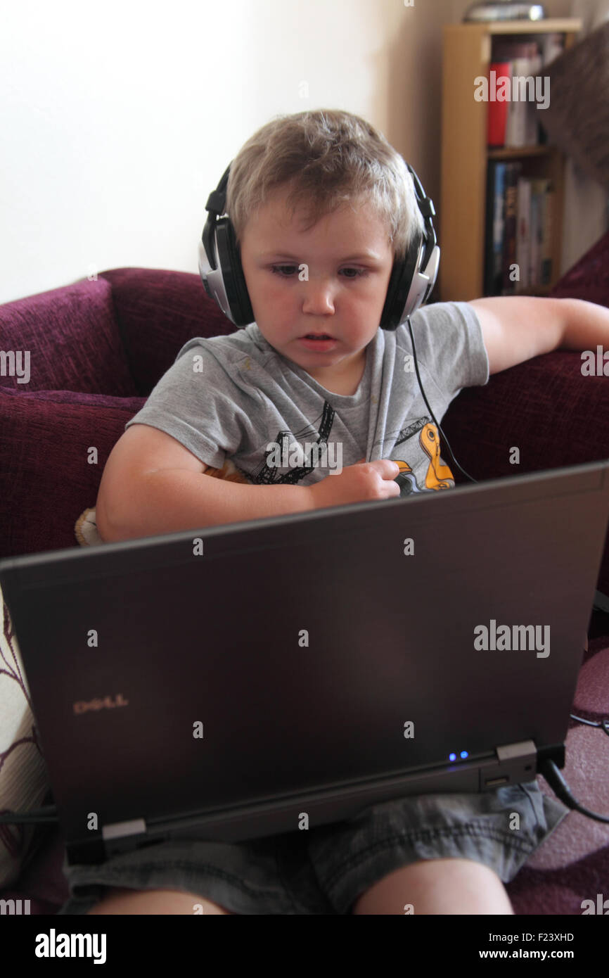 Small boy watching video on laptop computer with headphones Stock Photo ...