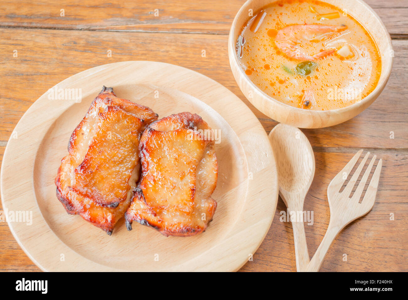 Chicken steak and spicy soup on wooden table, stock photo Stock Photo ...