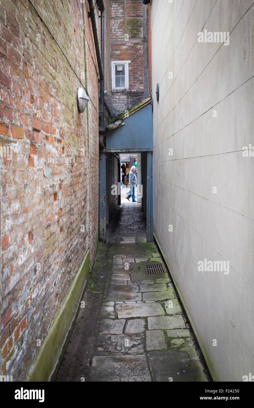 Man walks past the end of a long narrow passage between two buildings ...