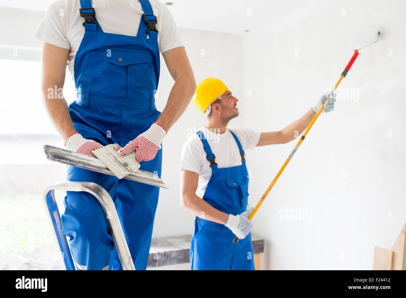 two builders with painting tools repairing room Stock Photo - Alamy
