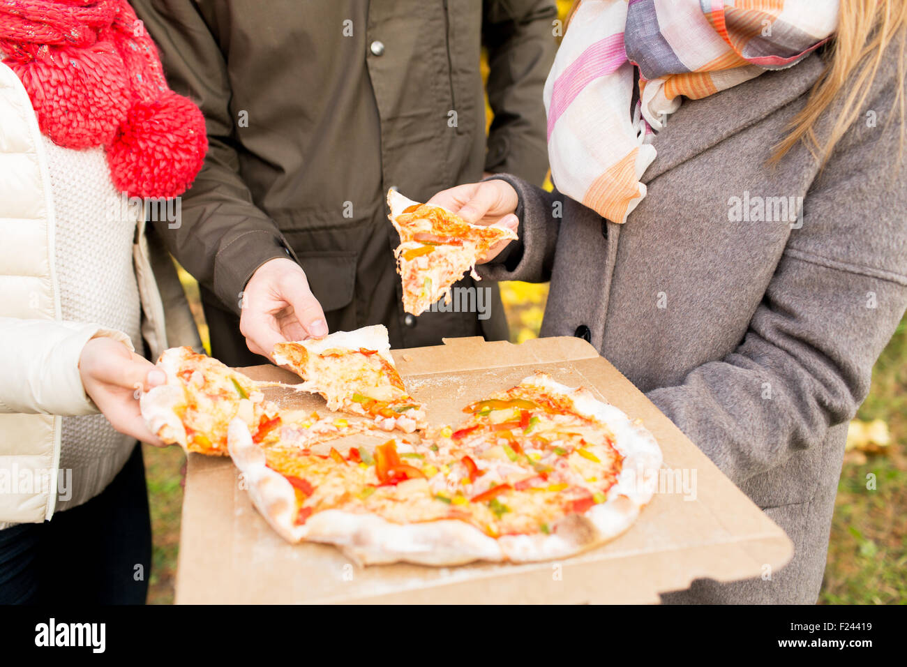 close up of friends hands eating pizza outdoors Stock Photo - Alamy