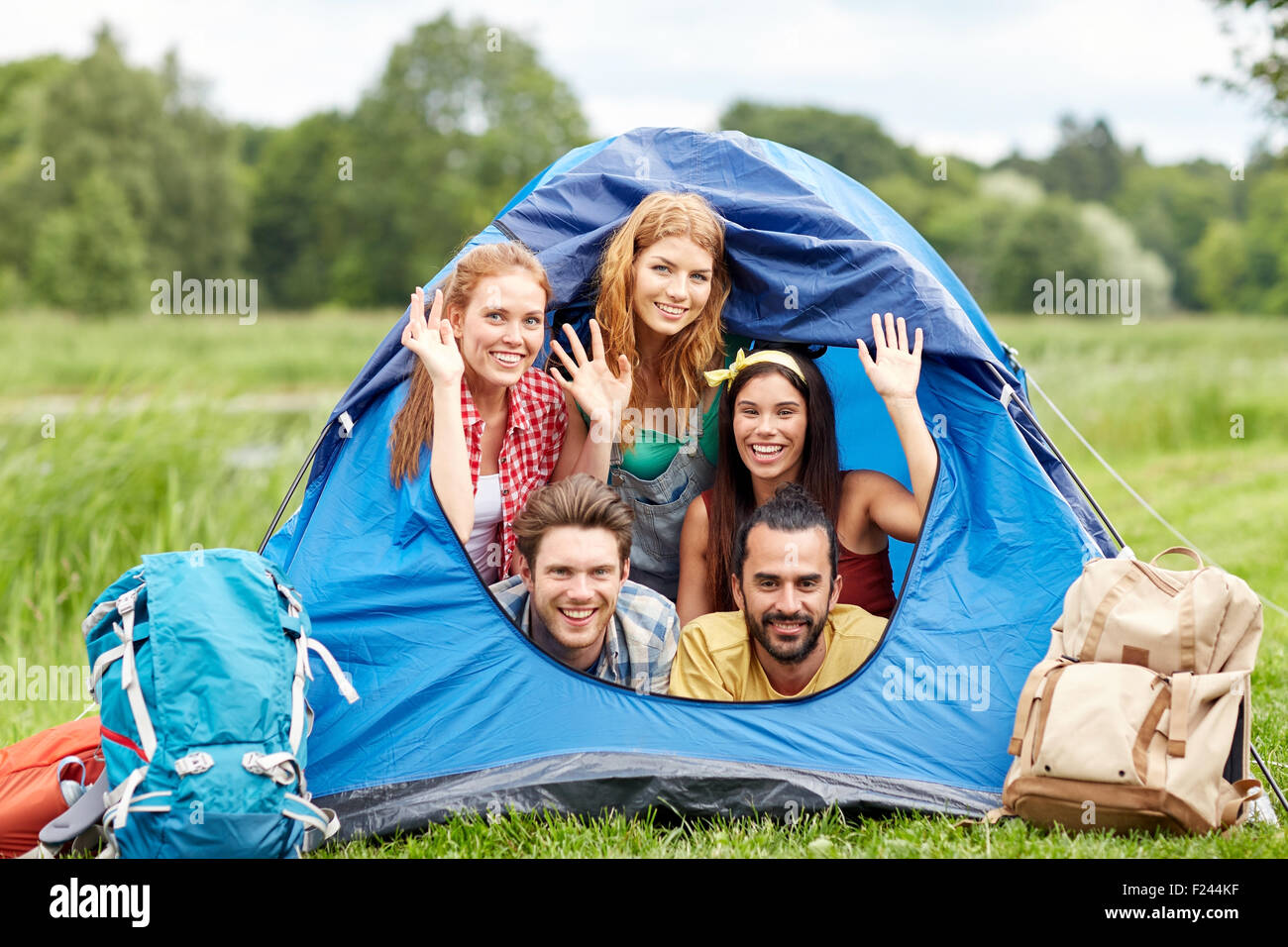 happy friends with backpacks in tent at camping Stock Photo - Alamy
