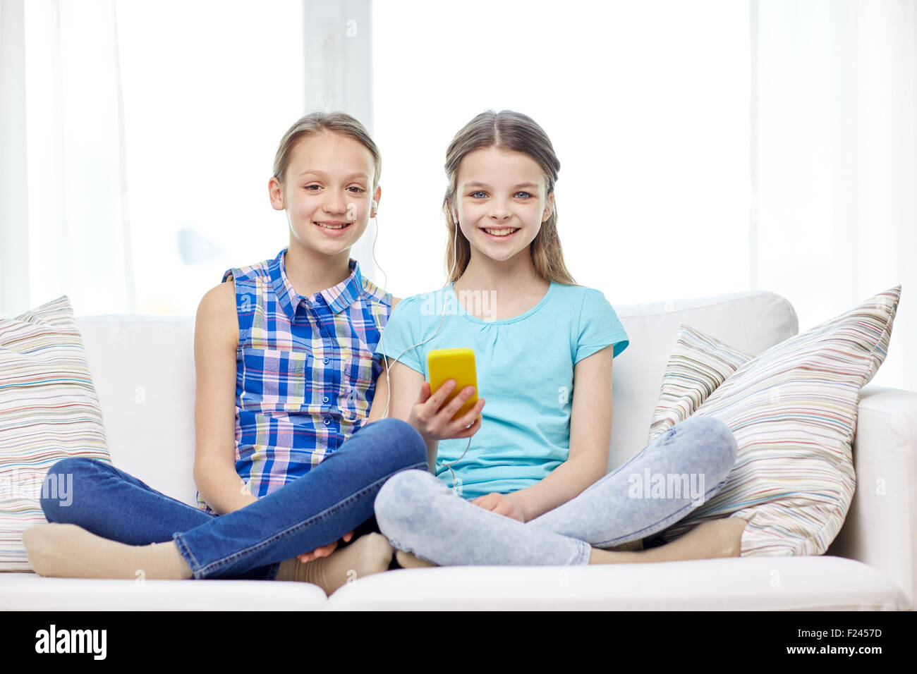happy girls with smartphone sitting on sofa Stock Photo - Alamy