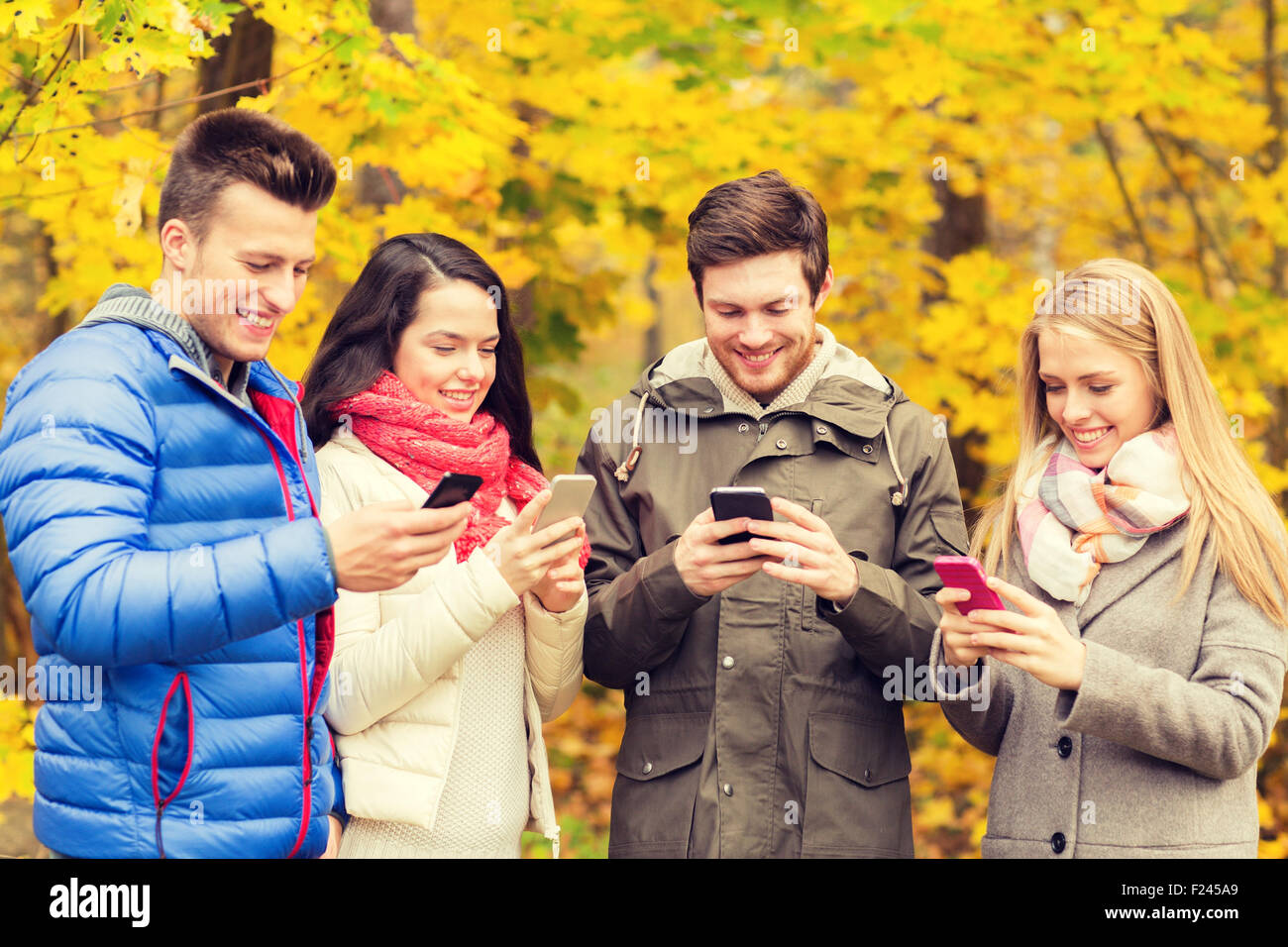 smiling friends with smartphones in city park Stock Photo - Alamy