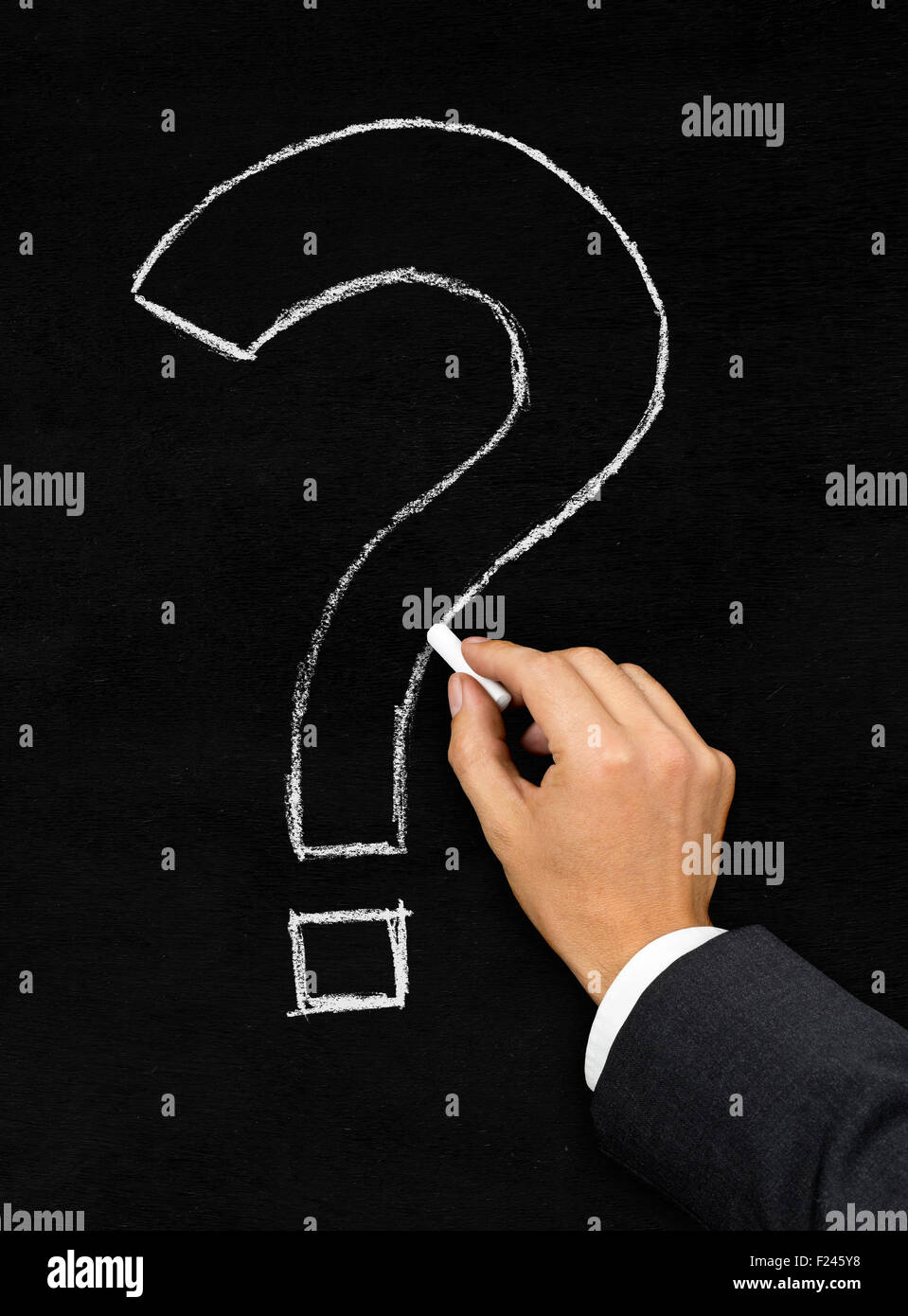 Male businessman drawing question mark with chalk on blackboard ...
