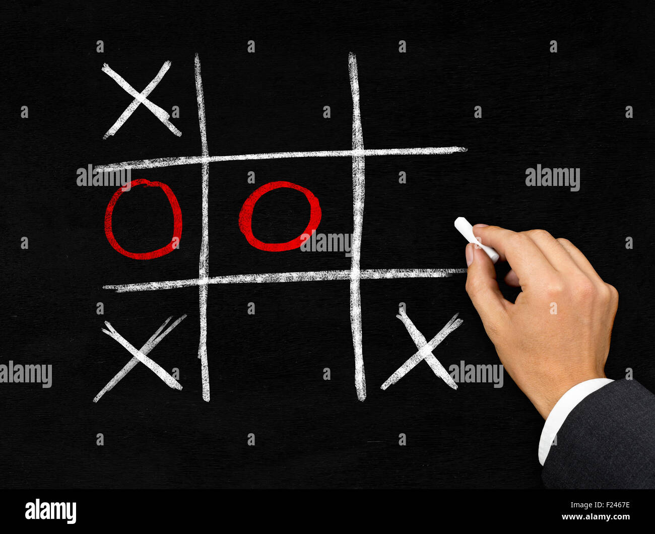 Man drawing tic-tac-toe game with chalk on blackboard background Stock ...