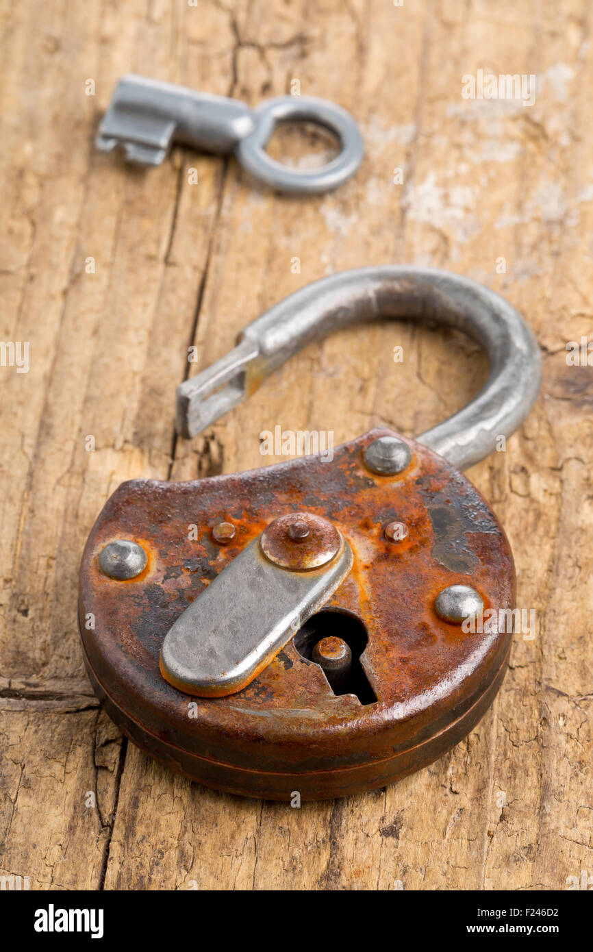 Old rusty padlock with open latch and key on wooden background Stock ...