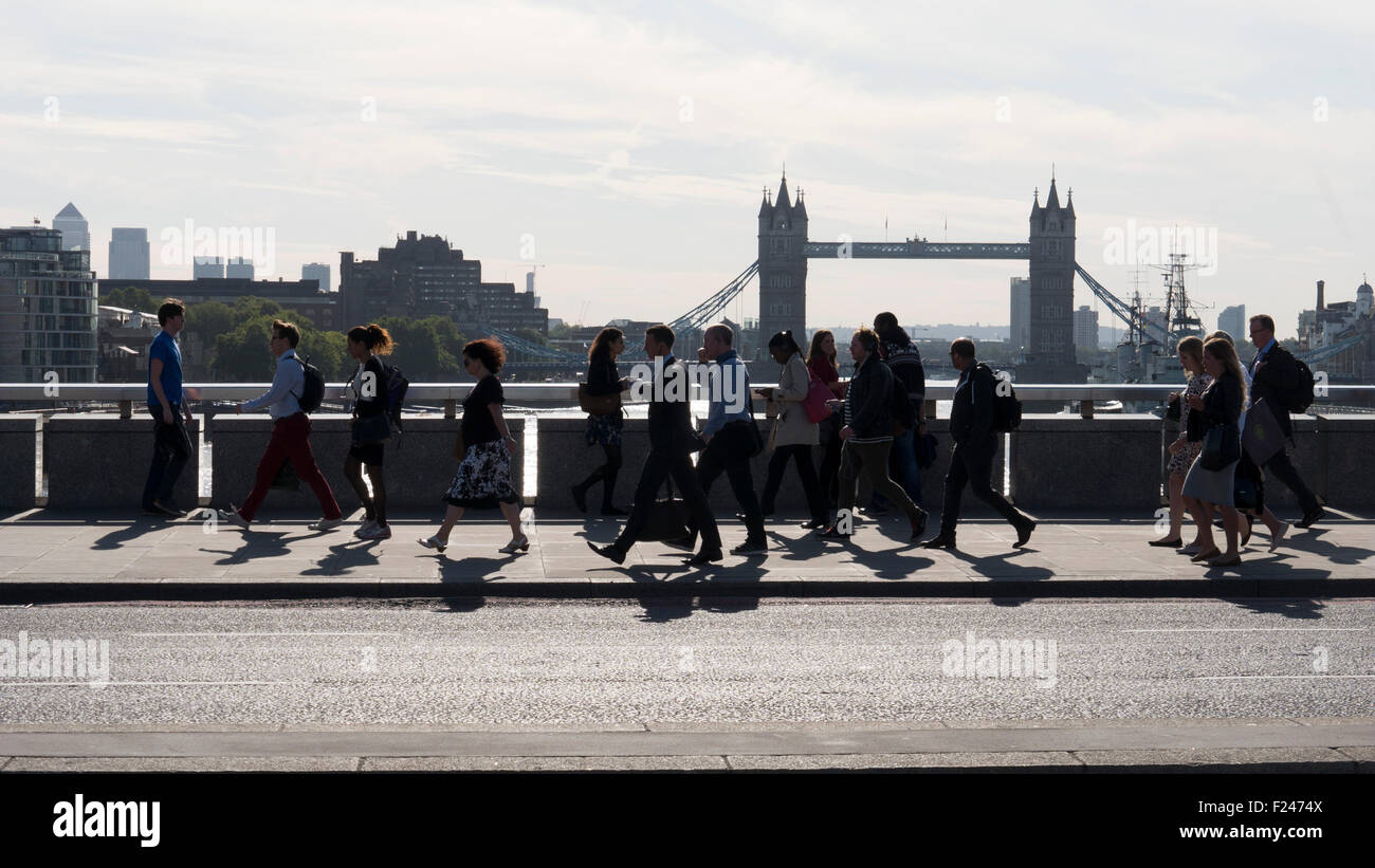 crowd of commuters and office workers crossing London Bridge on way to ...