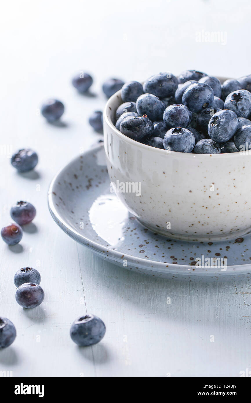 Spotted blue ceramic cup of blueberries with saucer at blue wooden ...