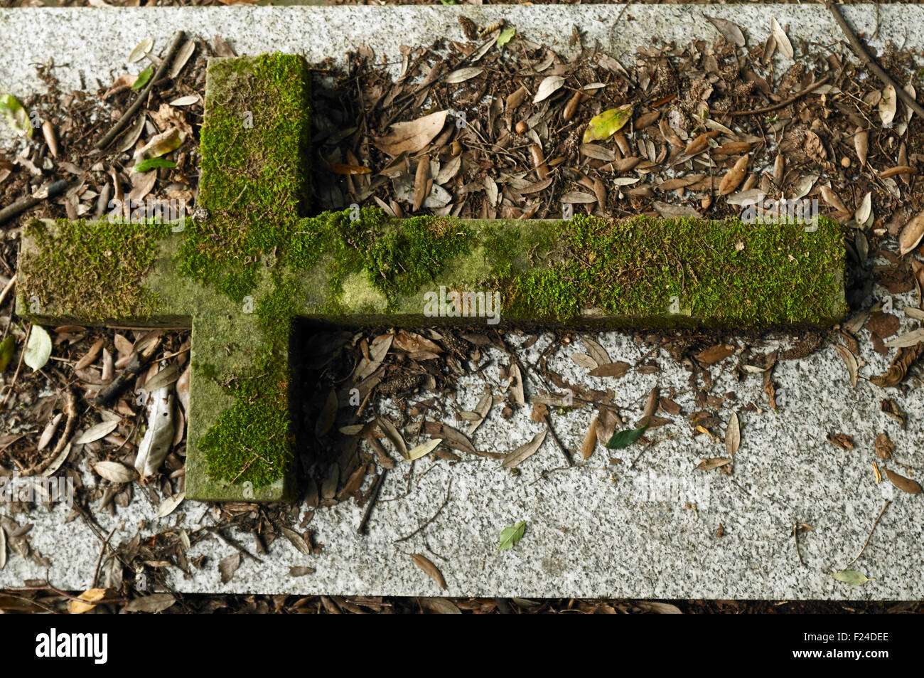 Moss covered cross in graveyard or cemetery with autumn leaves ...