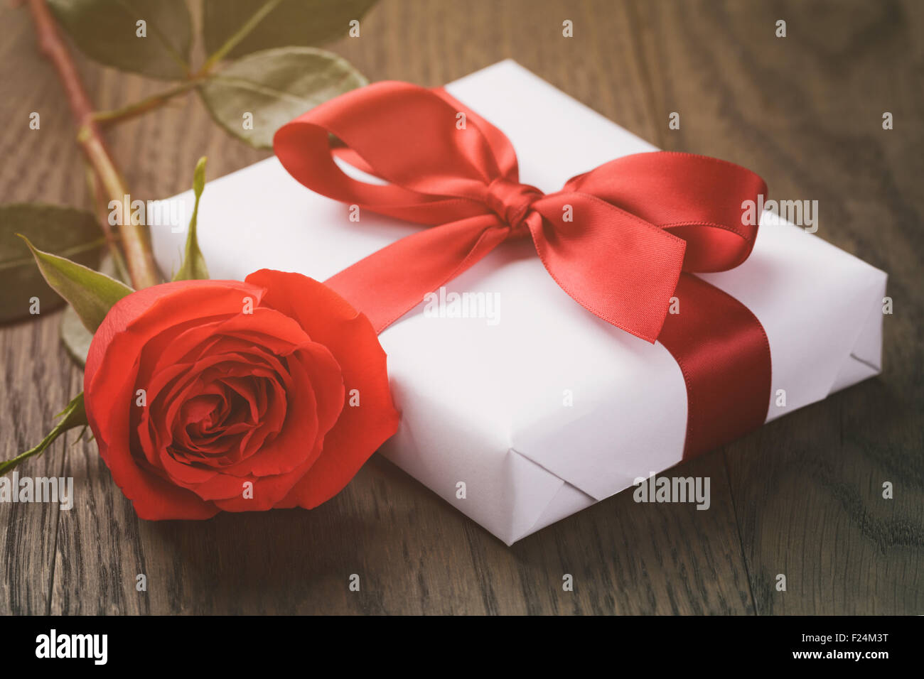 rustic present box with red ribbon on wood table Stock Photo - Alamy