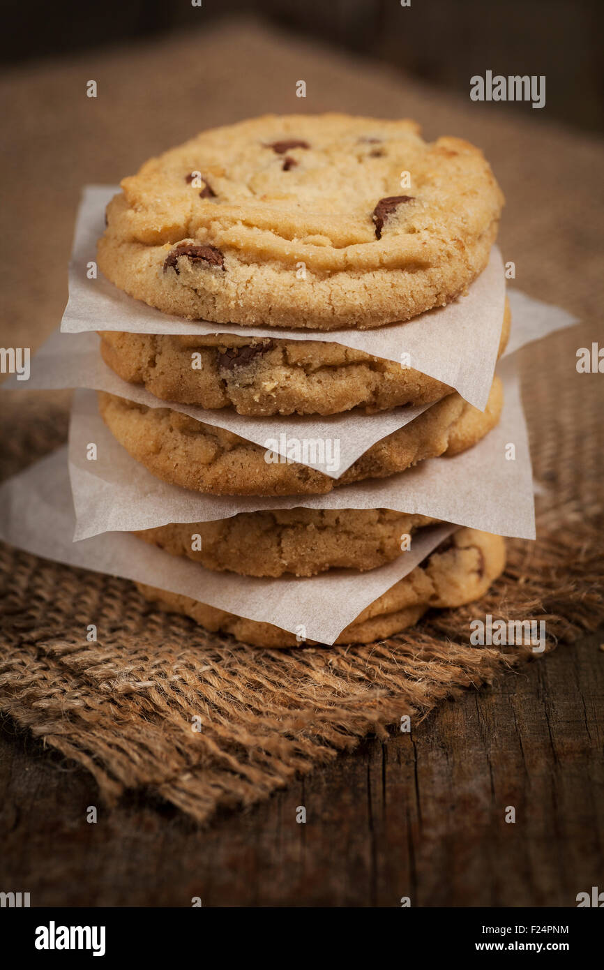 Stack of chewy chocolate chip cookies on a wooden table sat on hessian ...