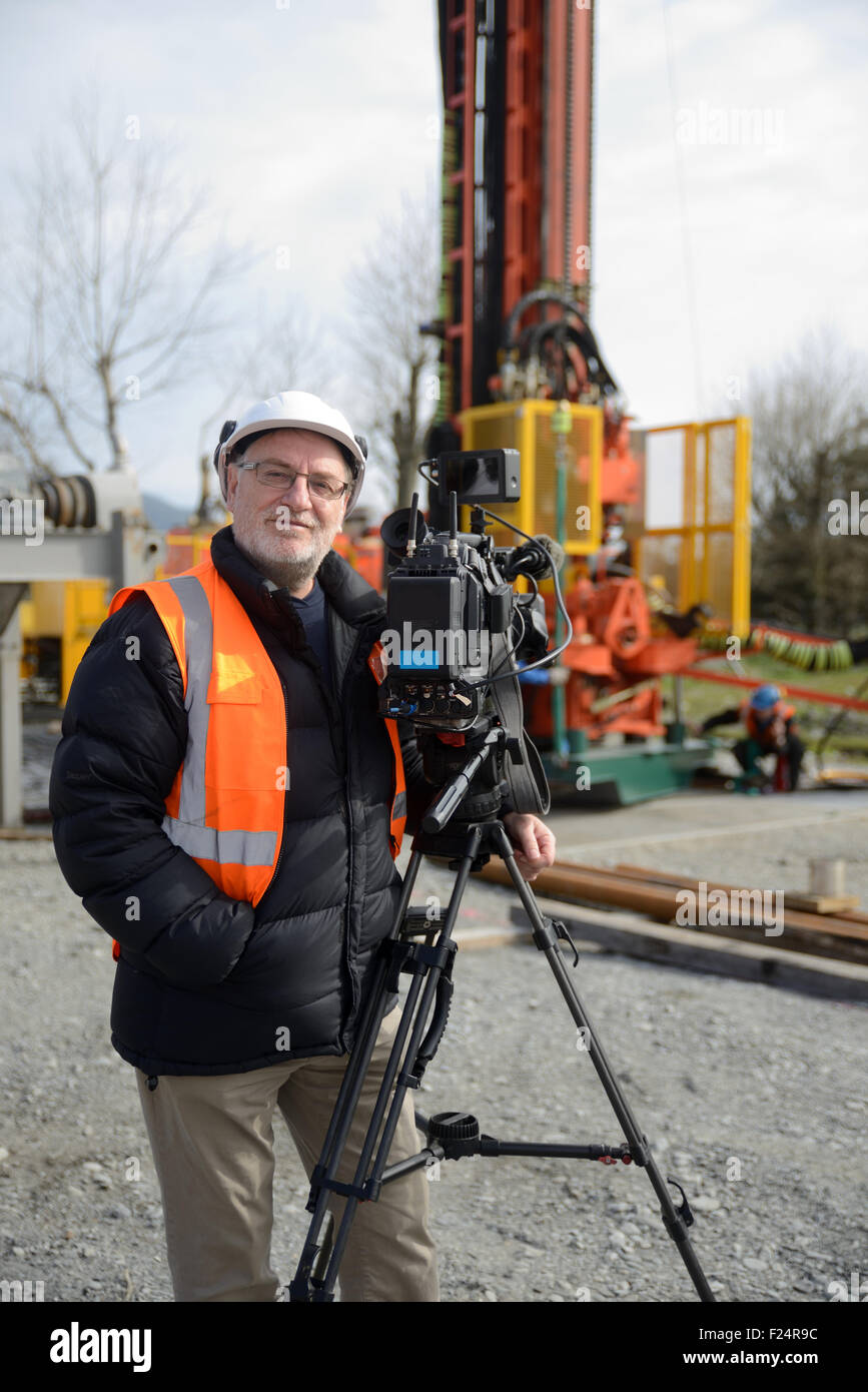 A documentary filmmaker poses with his camera on location at a drilling ...