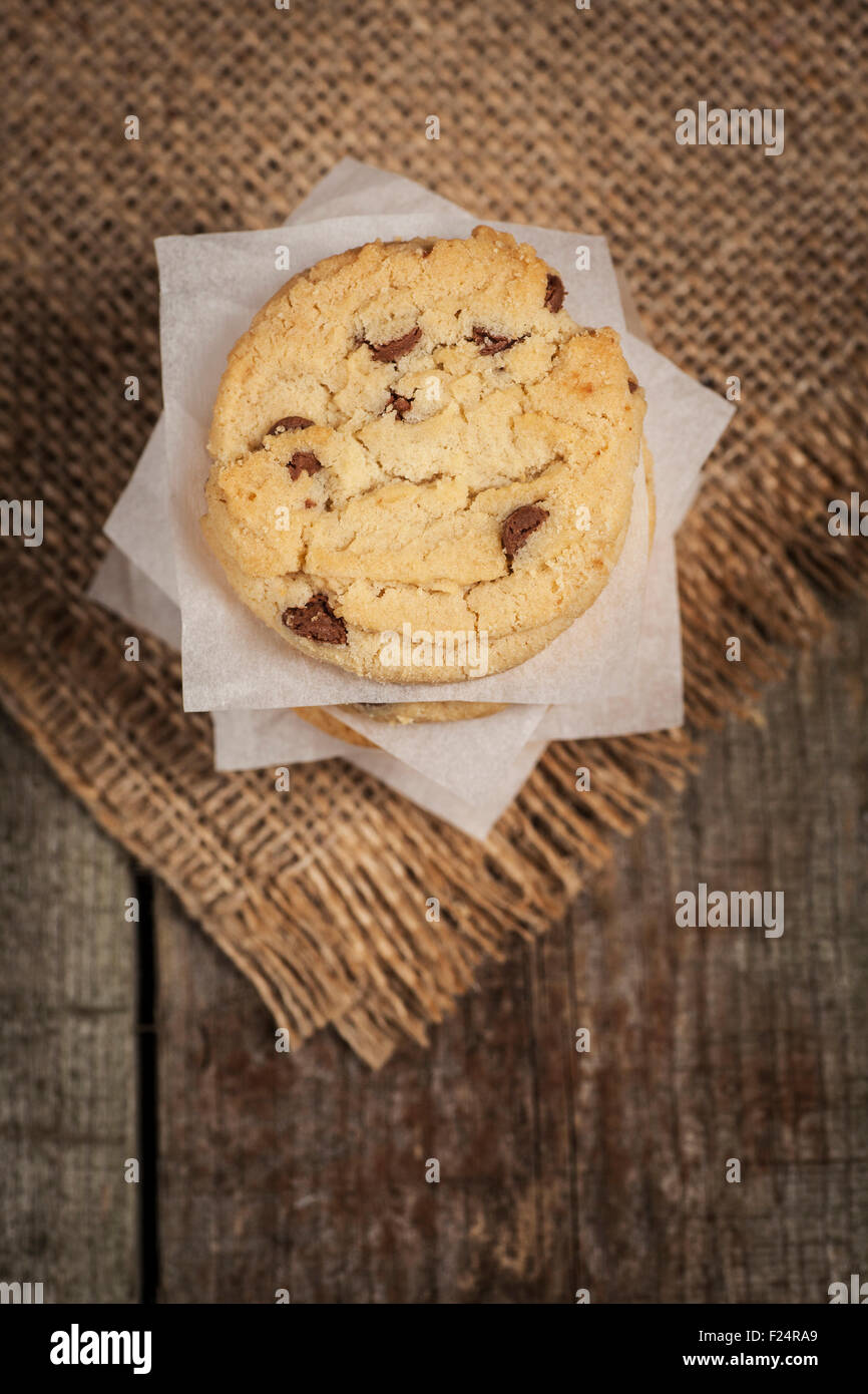 Stack of chewy chocolate chip cookies on a wooden table sat on hessian ...