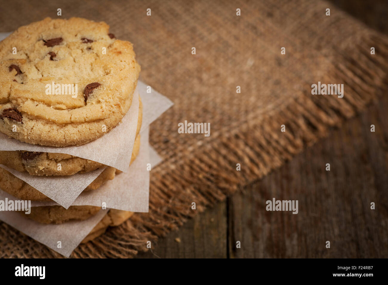Stack of chewy chocolate chip cookies on a wooden table sat on hessian ...