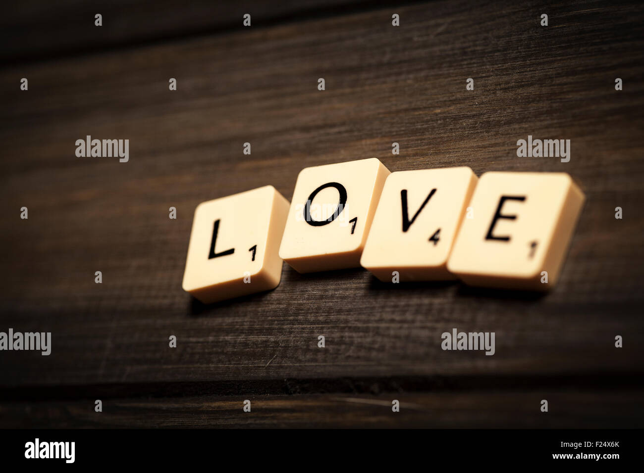 LOVE written in Scrabble letters on a dark wooden background. Copy ...