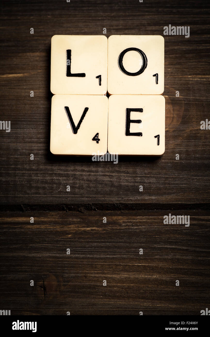 LOVE written in Scrabble letters on a dark wooden background. Copy ...