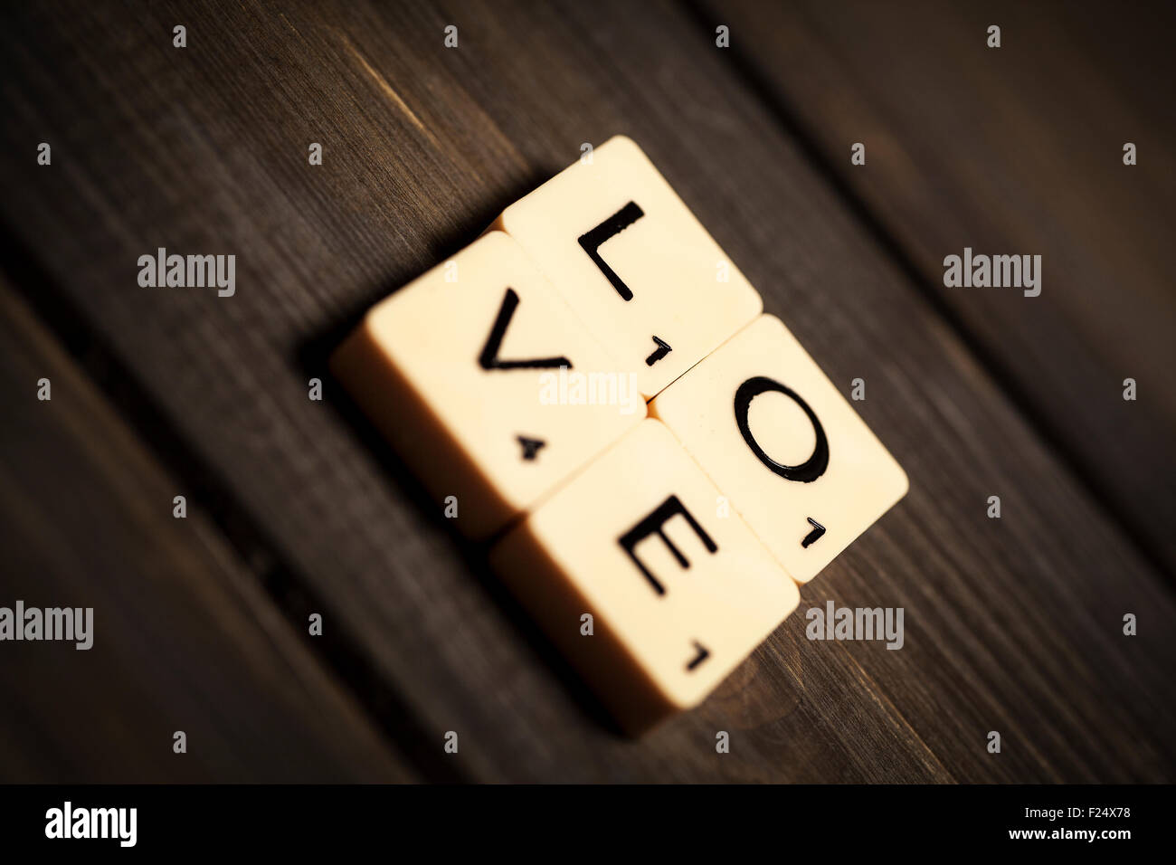 LOVE written in Scrabble letters on a dark wooden background. Copy ...