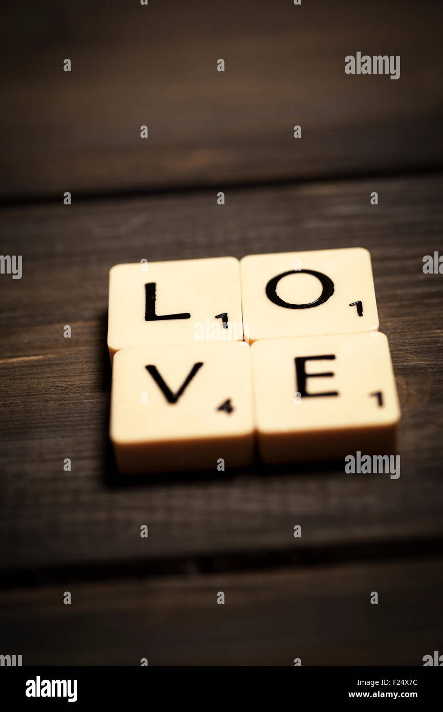 LOVE written in Scrabble letters on a dark wooden background. Copy ...