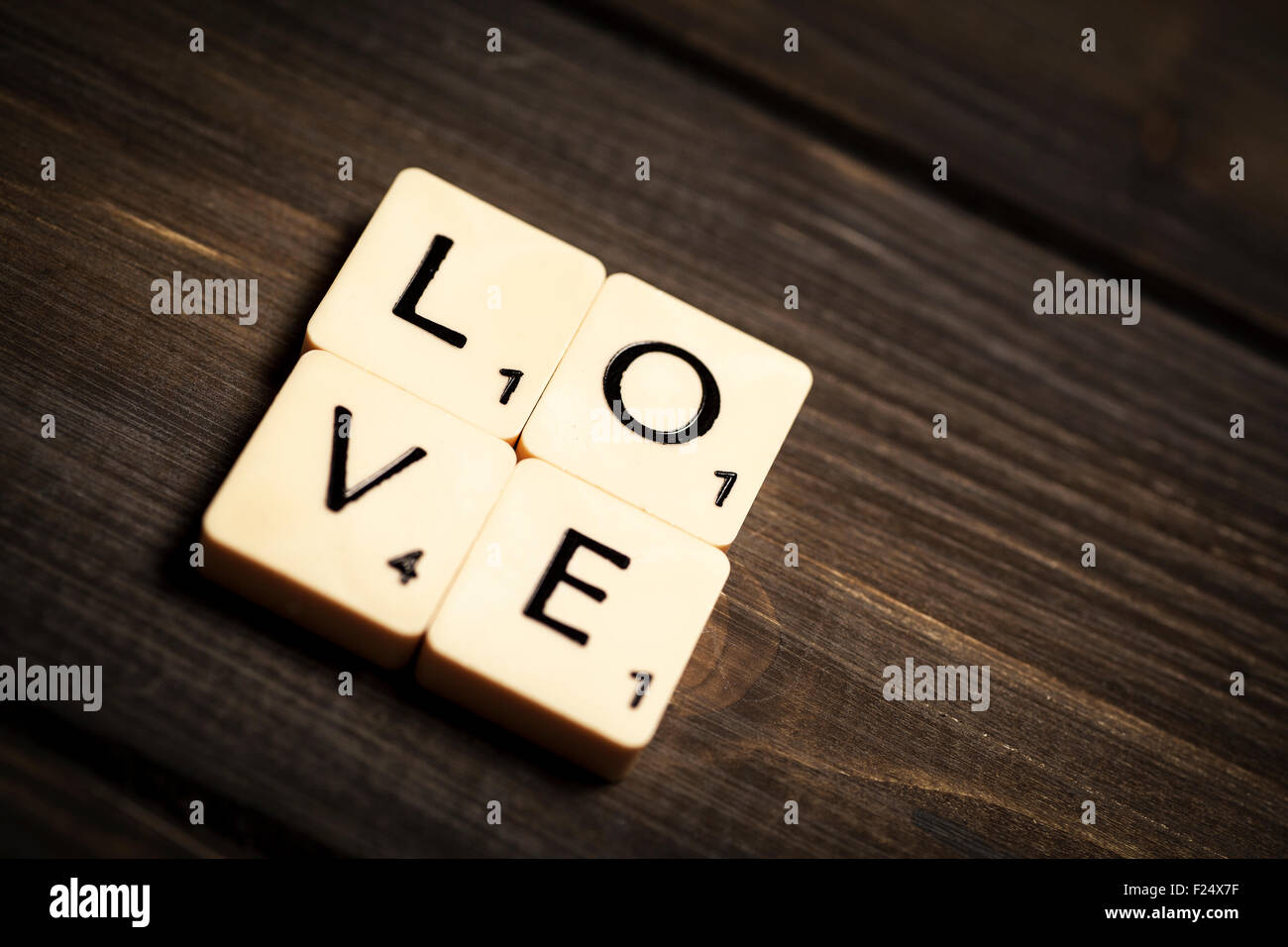 LOVE written in Scrabble letters on a dark wooden background. Copy ...