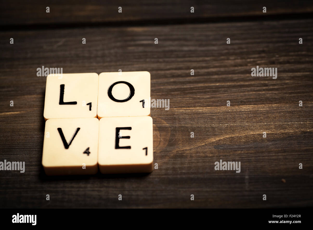 LOVE written in Scrabble letters on a dark wooden background. Copy ...