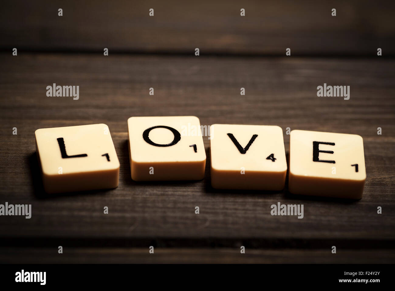 LOVE written in Scrabble letters on a dark wooden background. Copy ...