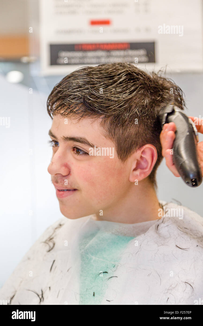 Cute caucasian teenage boy sitting at the hairdresser salon for a ...