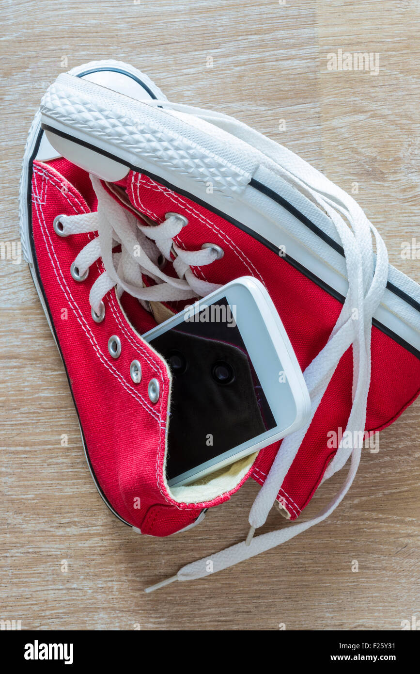 Pair of red sneakers and a smart phone seen from above on a parquet ...