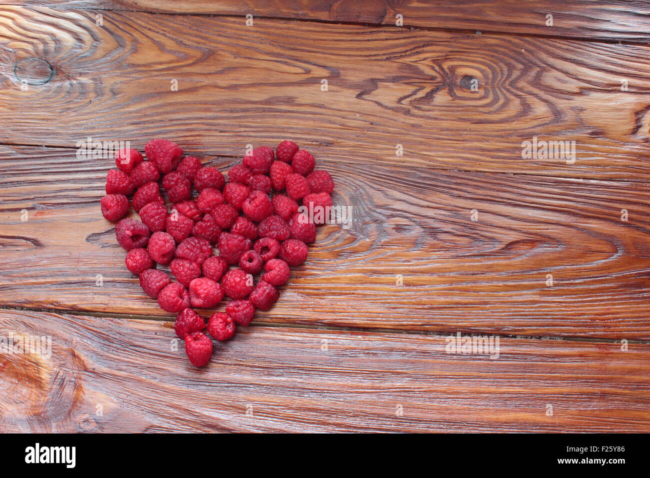 on a wooden board lined heart of raspberries Stock Photo - Alamy
