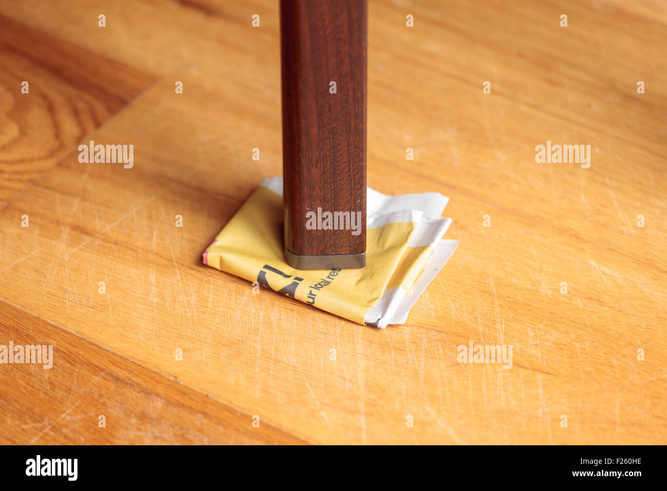 Leg of a wobbly table supported by folded paper Stock Photo - Alamy