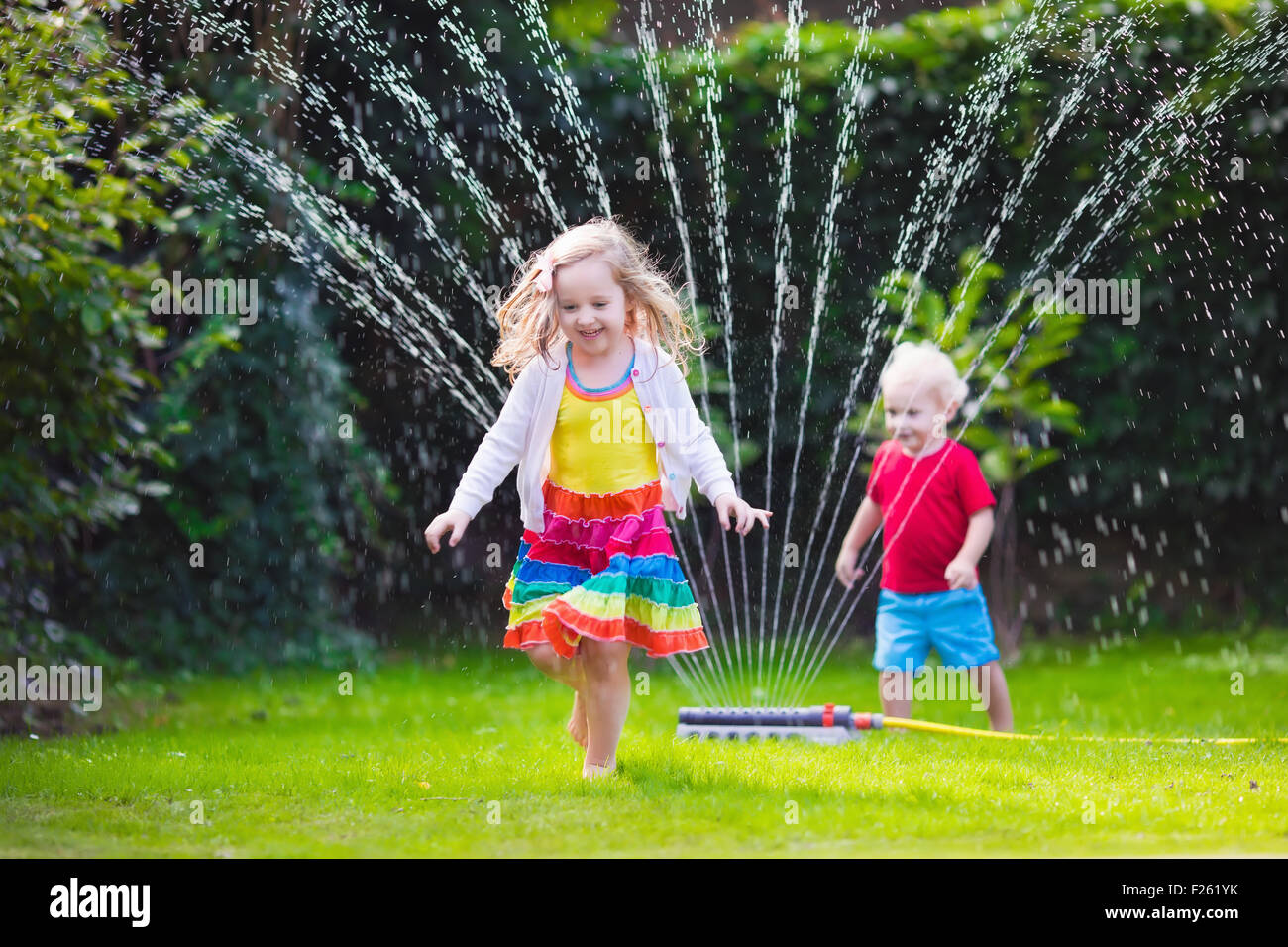 Child playing with garden sprinkler. Preschooler kid running and ...