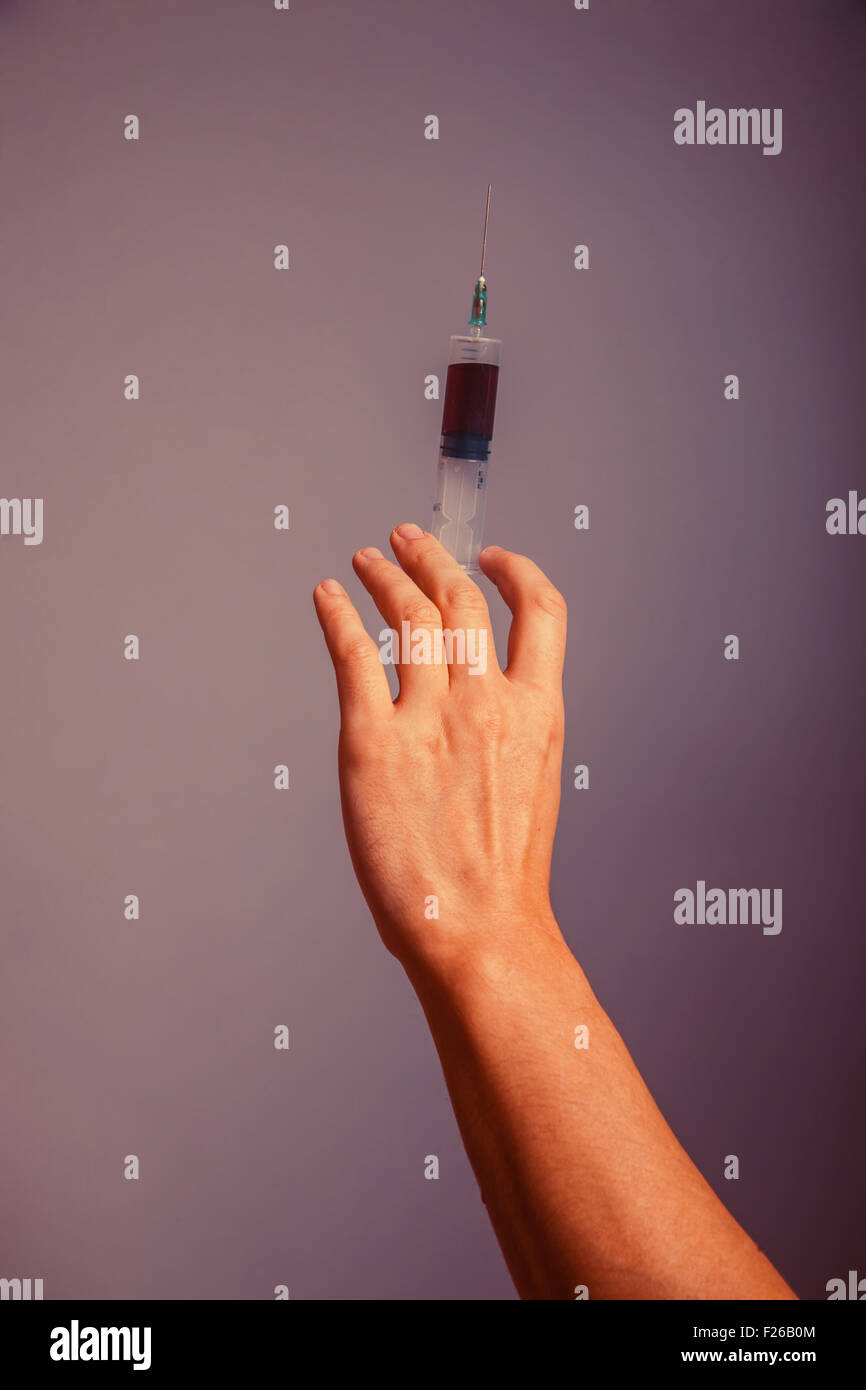human hand holding a syringe with a drug on a gray background re Stock ...