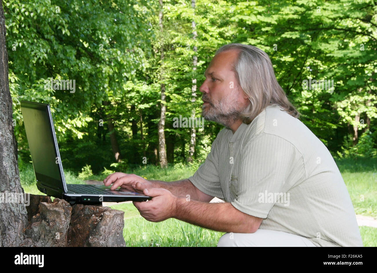 Man with a laptop sitting under the tree Stock Photo - Alamy