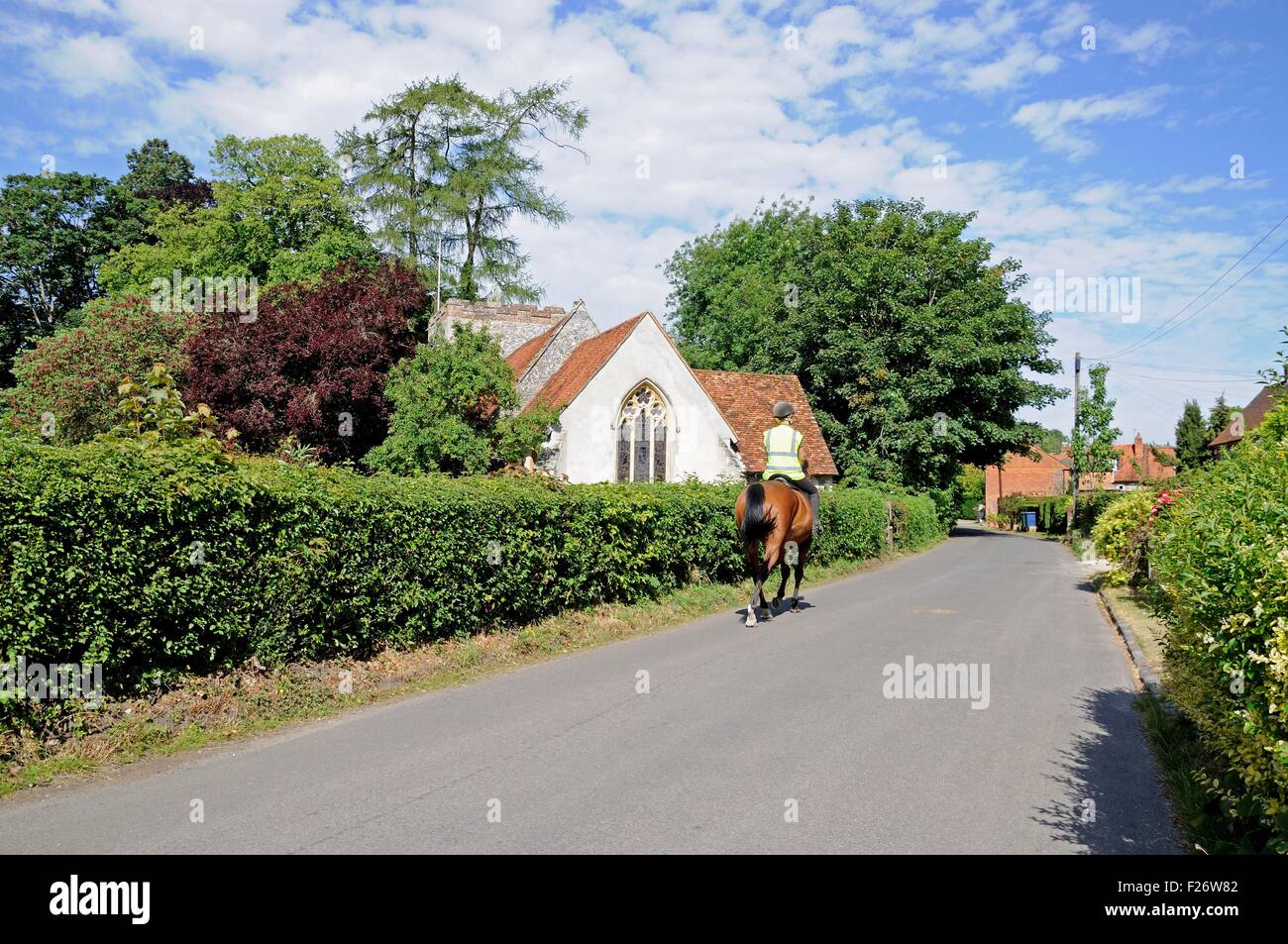 Horse rider passing the St Mary the Virgin church in the village centre ...