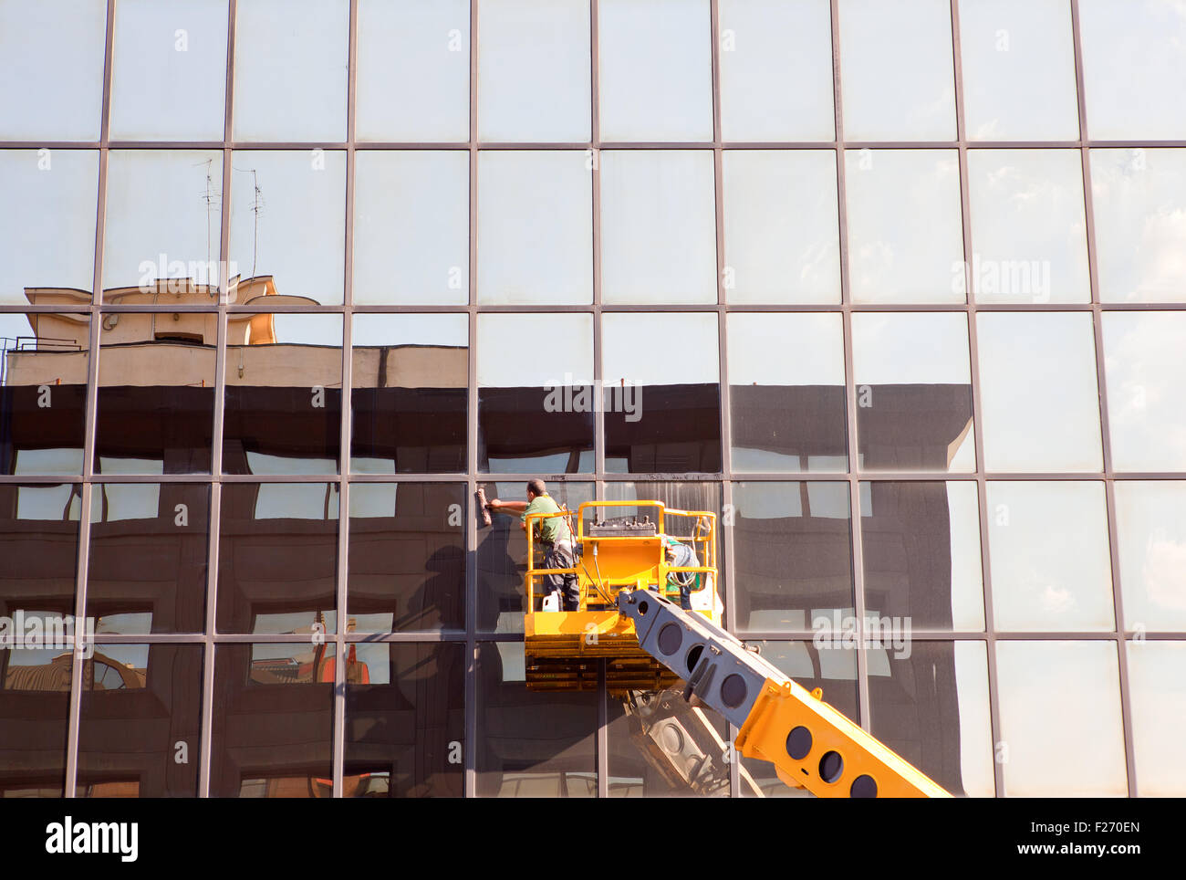 Men cleaning building's windows on a crane Stock Photo - Alamy