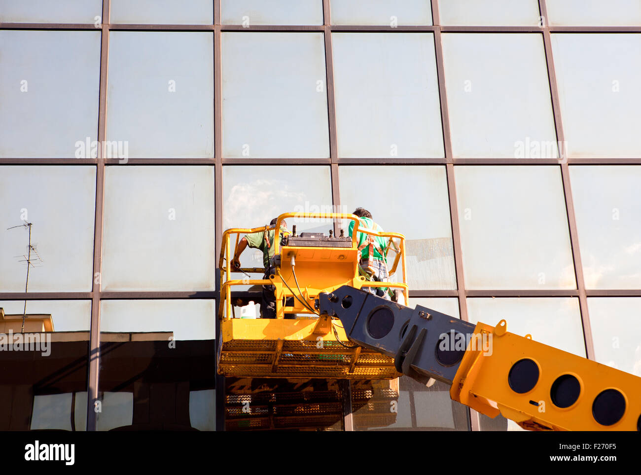 Men cleaning building's windows on a crane Stock Photo - Alamy