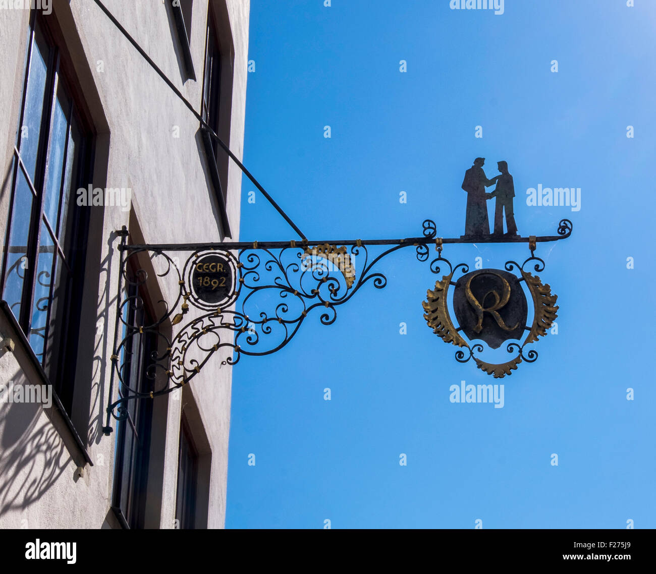 Decorative wrought iron metal shop sign against blue sky. Füssen Town ...
