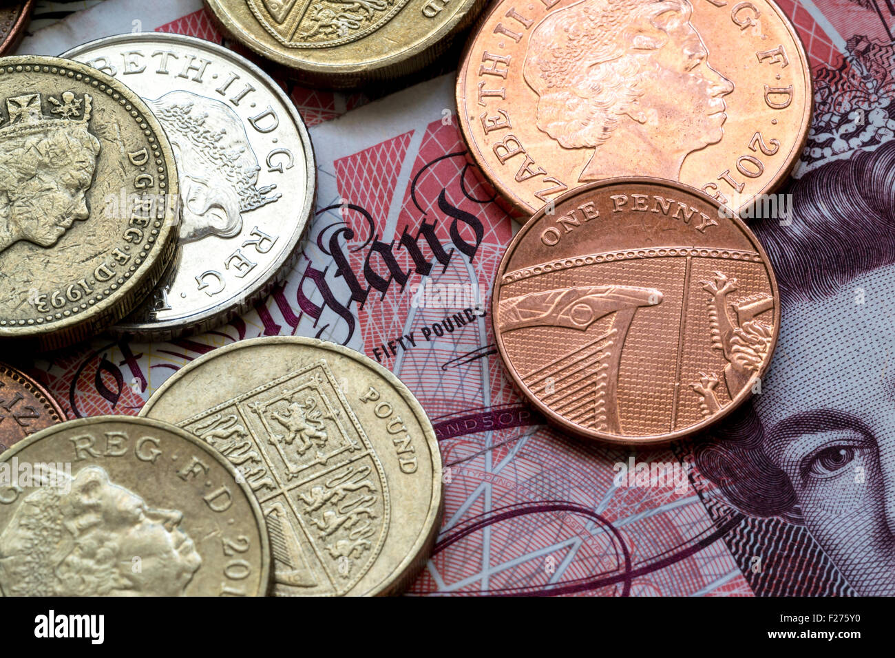 Assorted English Coins of varying values lay on top of a British Fifty ...