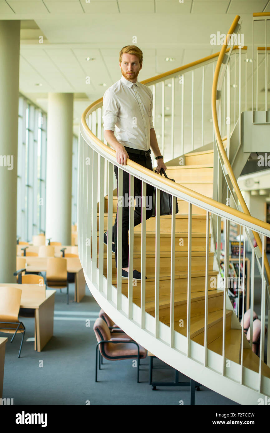 Young man on the stairs in library Stock Photo - Alamy