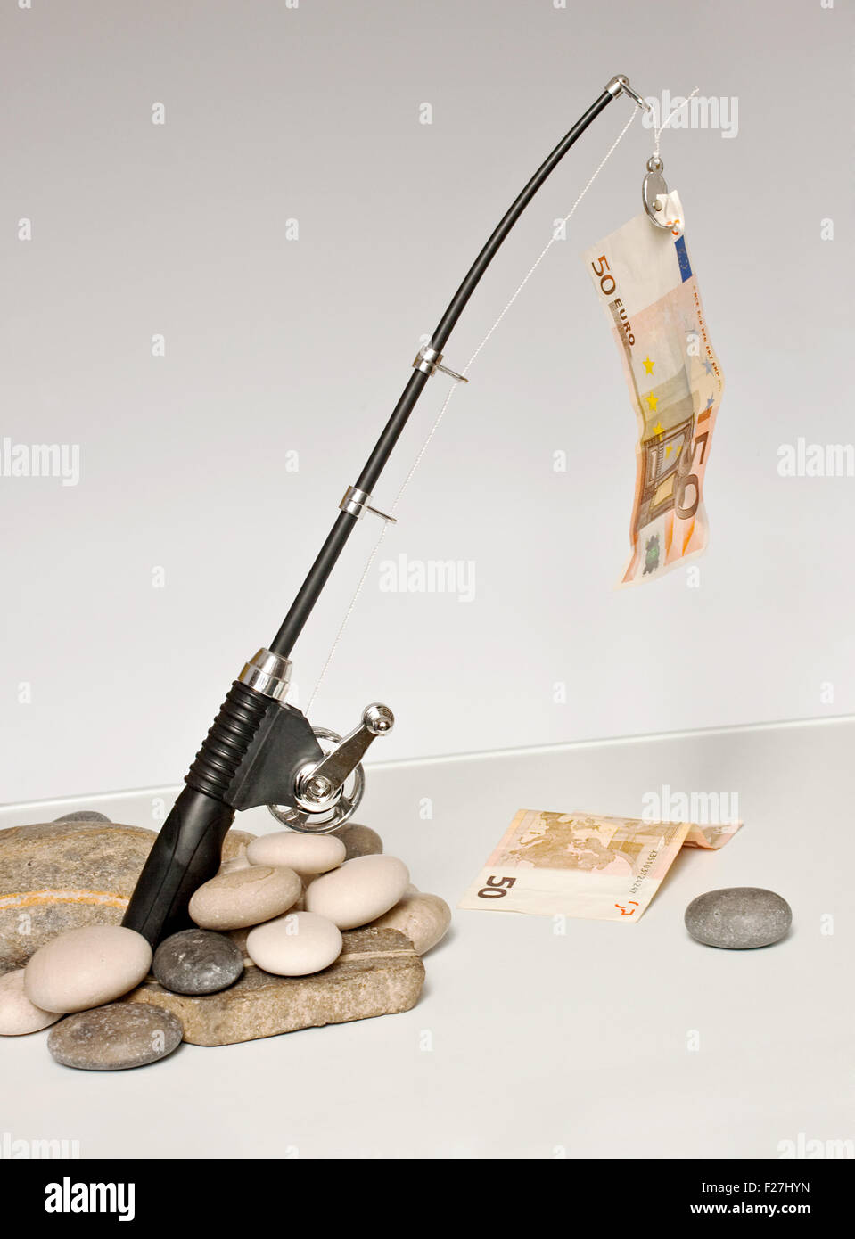 Fishing rod while fishing euro bill on white background Stock Photo - Alamy