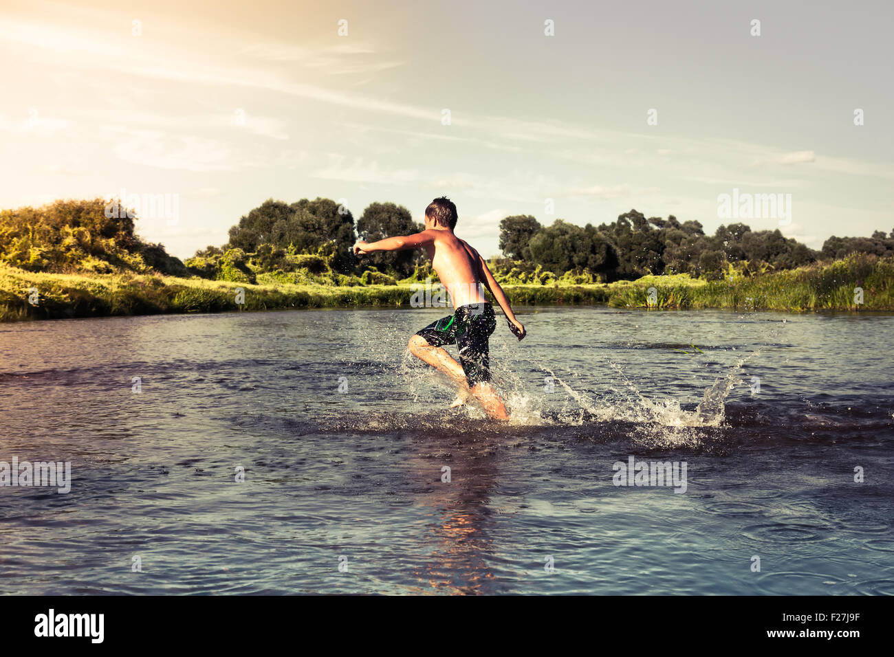 Young boy running forward on river shore during sunset Stock Photo - Alamy