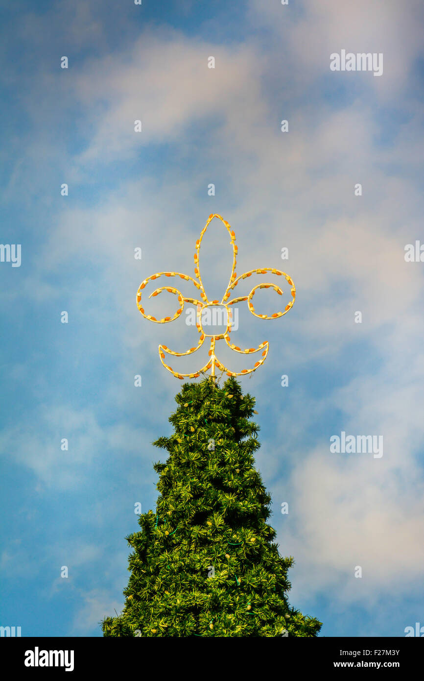 Fleur de Lis decoration with lights sits atop an evergreen tree strung ...