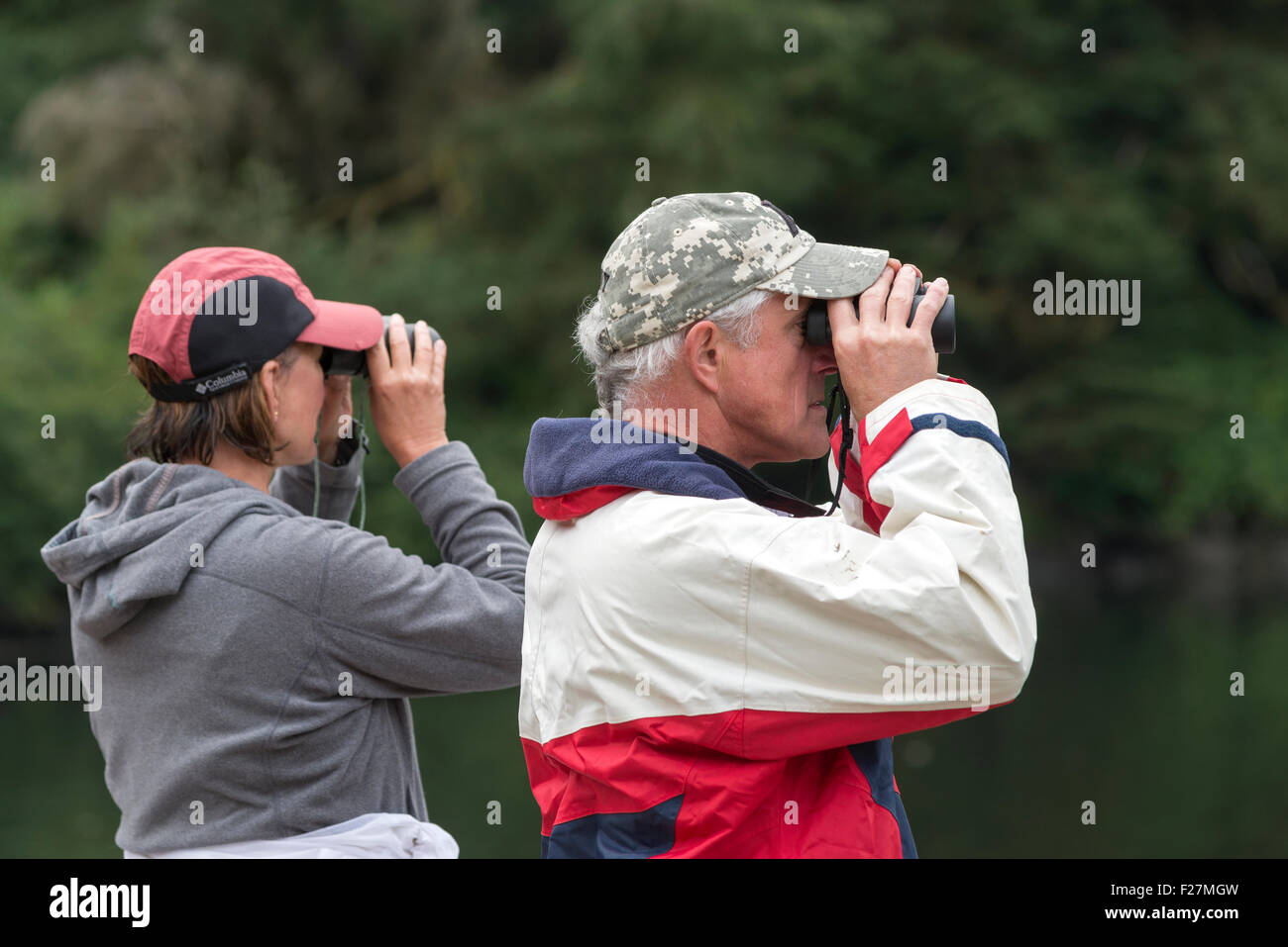 Couple using binoculars to watch wildlife in Alaska Stock Photo - Alamy