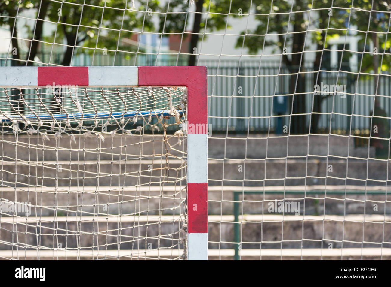 A red and white metal corner of a goal post and bar in front of a net ...