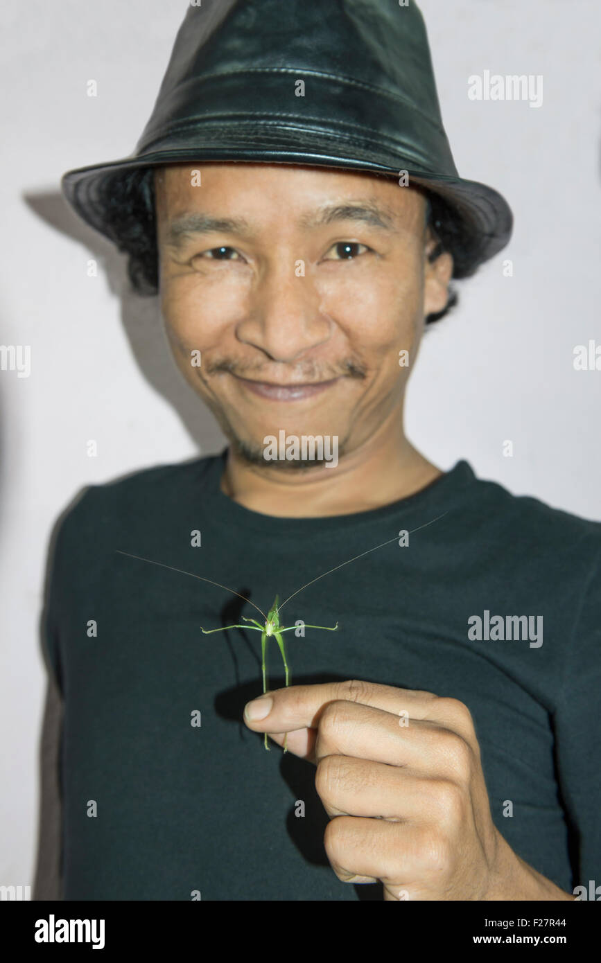 Portrait of a mid adult man holding grasshopper and smiling, Nepal ...