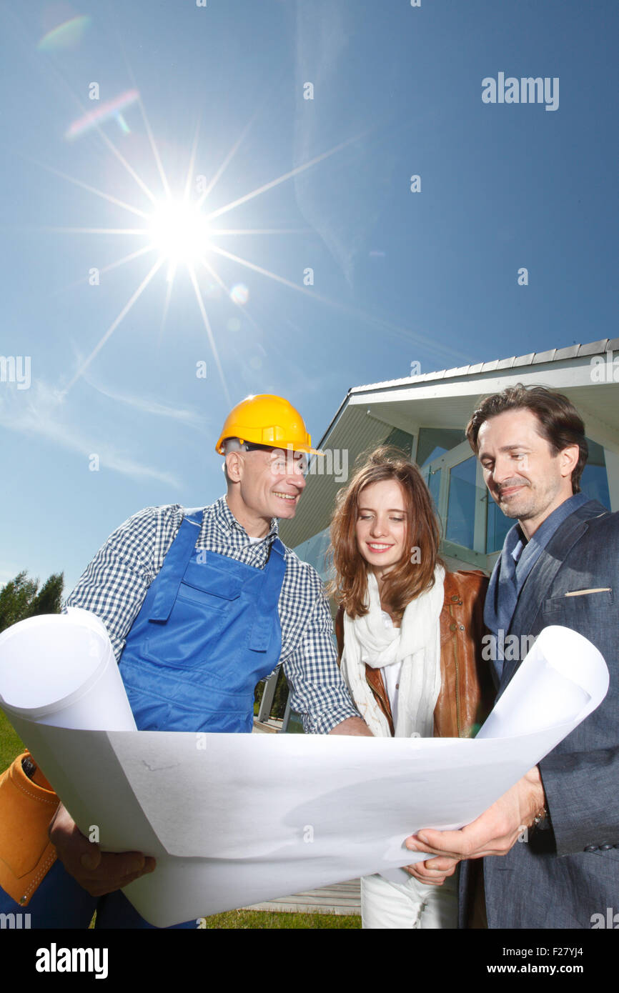 foreman shows house design plans to a young couple Stock Photo - Alamy